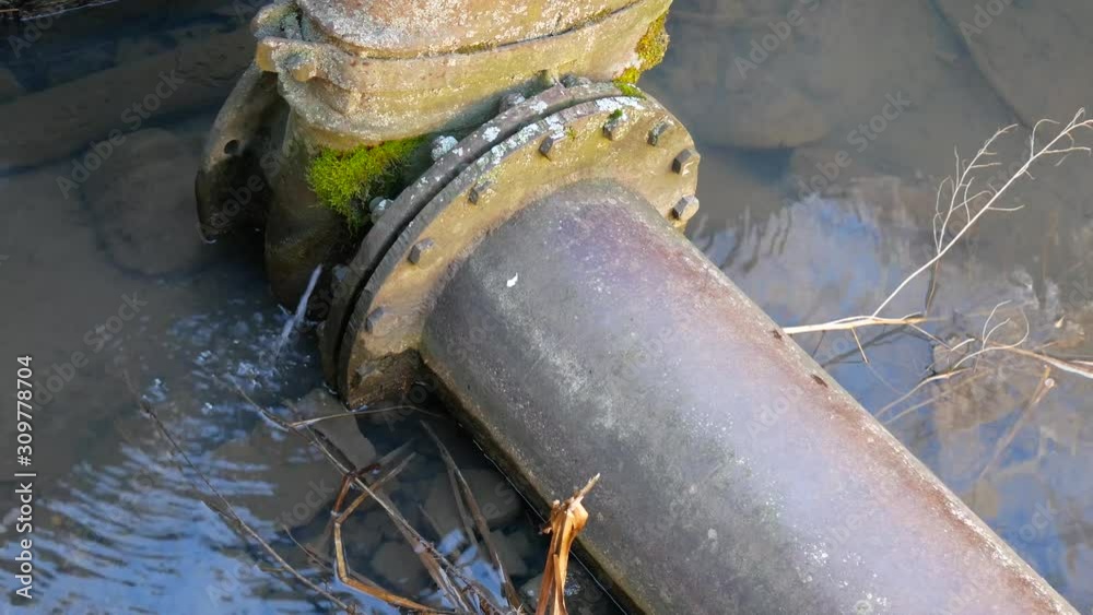 Leaking industrial pipe transporting the sewage water in a concrete pit ...