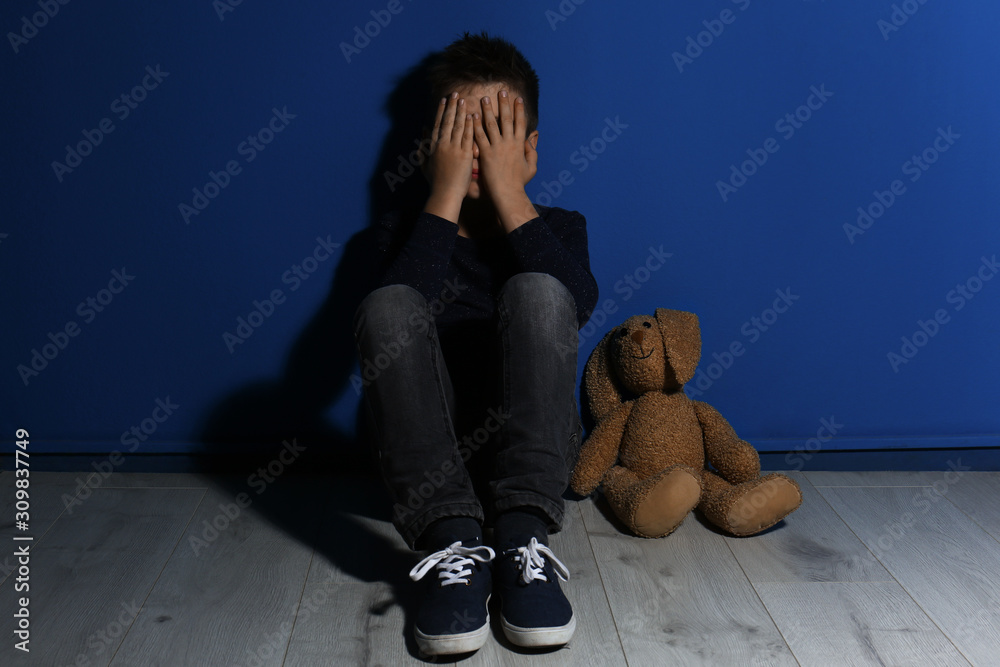 Abused little boy crying near blue wall. Domestic violence concept ...