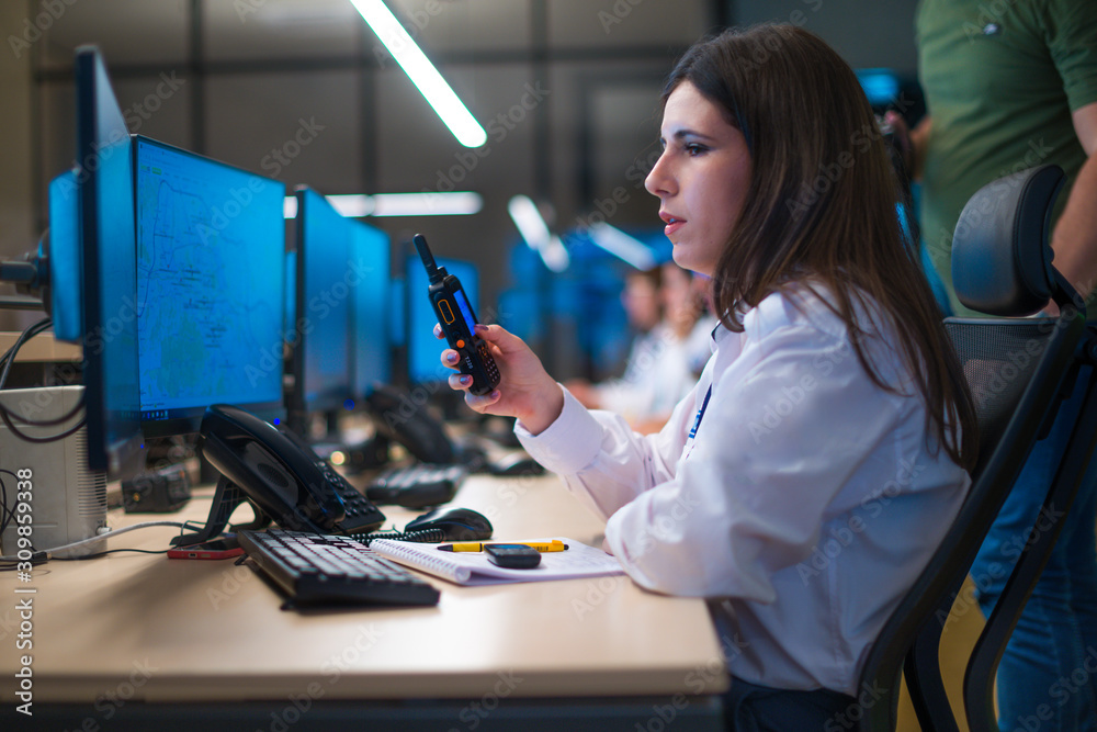Female security guard sitting and monitoring modern CCTV cameras in a ...