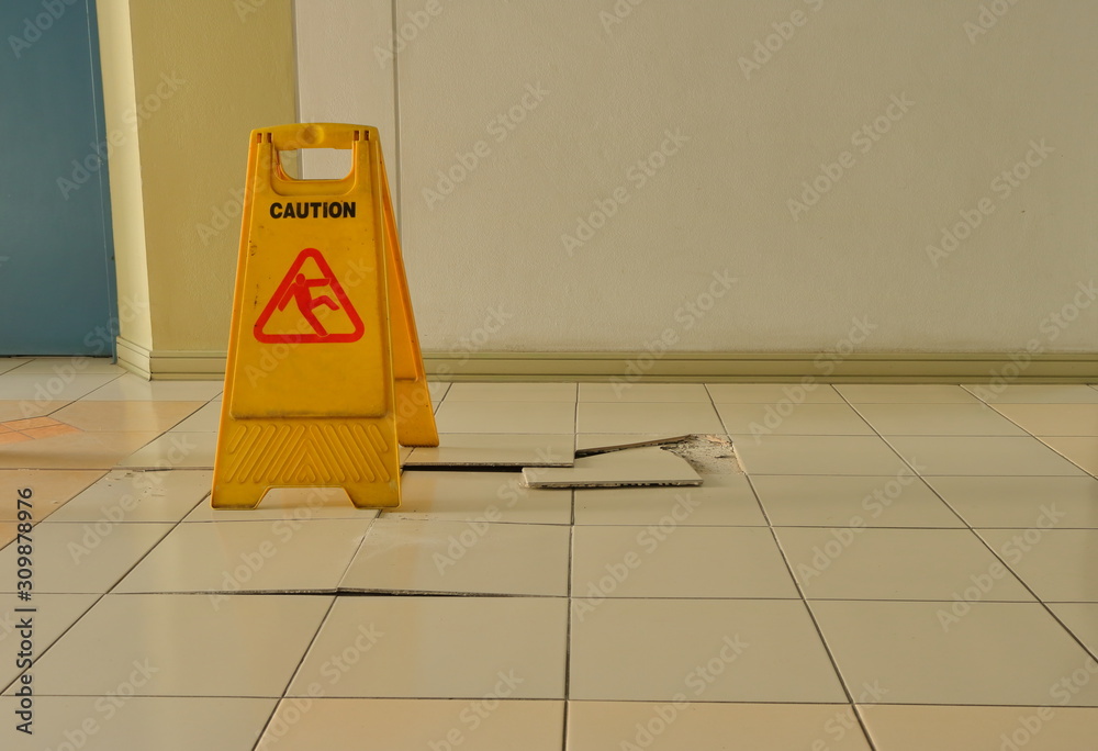 Closeup buckled and broken tiles on corridor near elevator with a ...