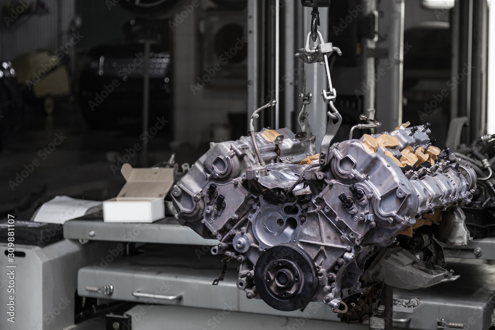 Used v8 engine with eight cylinders suspended mounted on a crane for ...