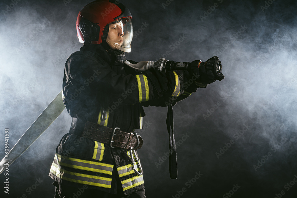 handsome fireman in helmet stand isolated in smoky space, wearing ...