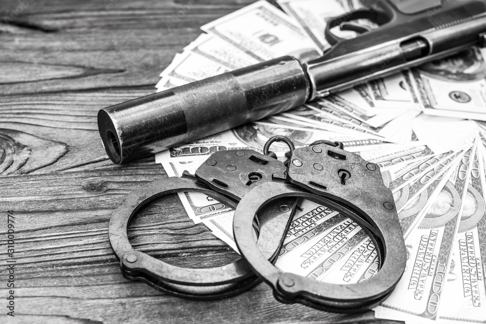 Foto Stock a pistol with a silencer, handcuffs, lies on a dollar money ...