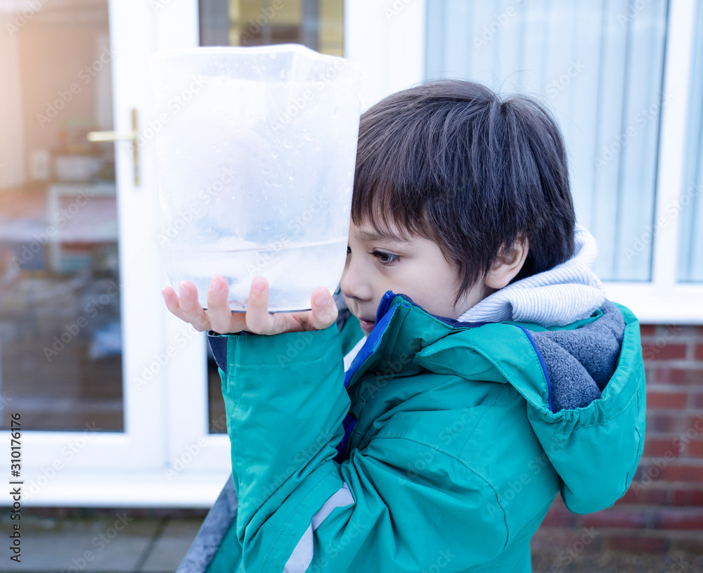 Cropped shot boy holding measuring jug pointing at level of rain ...