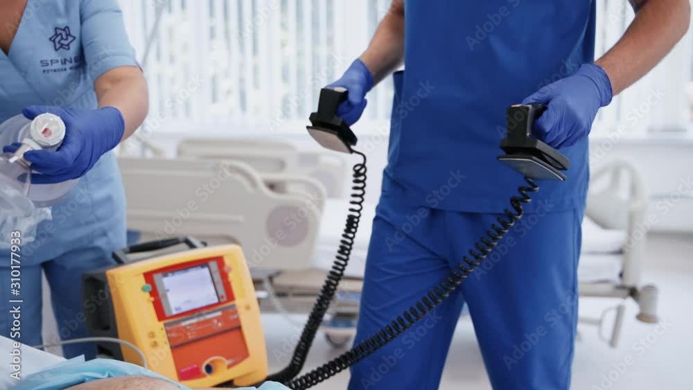 Reanimation of patient with defibrillator. Doctor using external ...