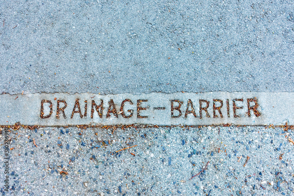Drainage barrier sign on concrete slab between asphalt pavement ...