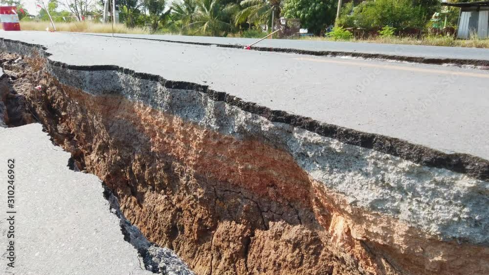 Asphalt road collapsed and fallen. Road collapses with huge cracks ...