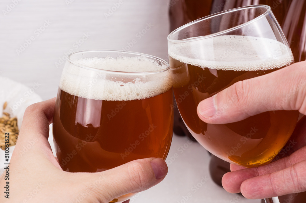 homemade craft beer in wineglass in two hands on white background. Ale ...