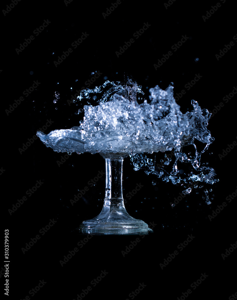 splash and spatter of water in a crystal vase on a black background ...