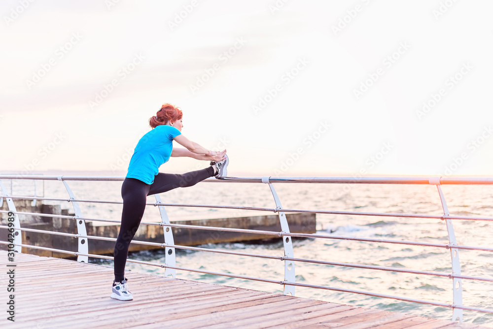Young girl with long red ponytail hair in blue shirt and black leggins ...
