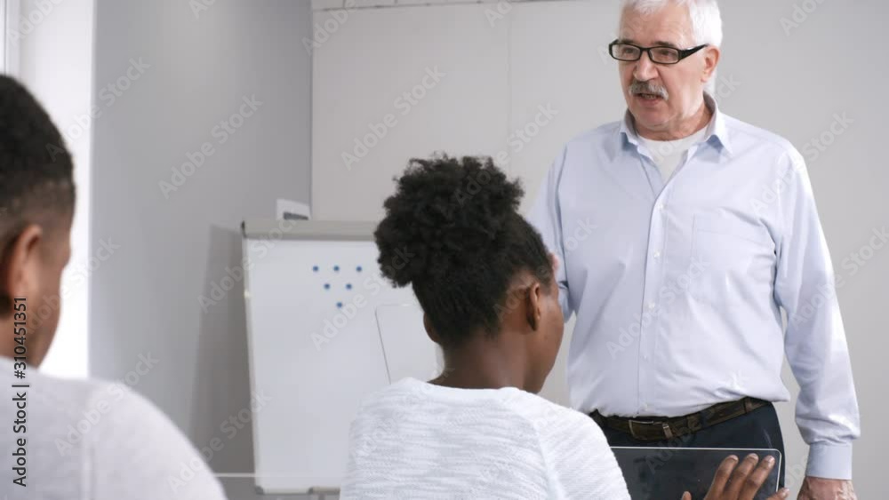Over-shoulder tilting medium shot of strict senior Caucasian male ...