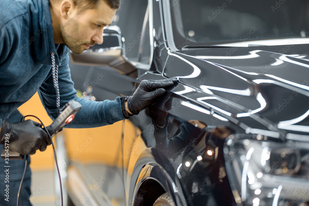 Car service worker examining vehicle body for scratches and damages ...