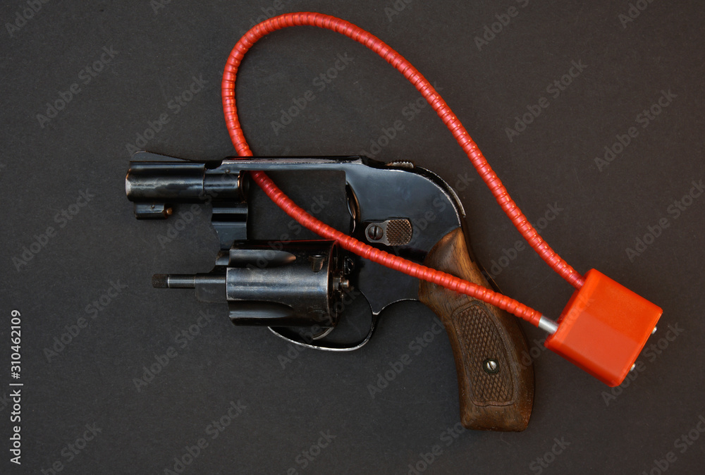 Black snubnose revolver with cable lock isolated on black background ...
