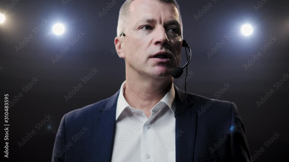 Portrait of men speaking through a microphone in dark conference hall ...