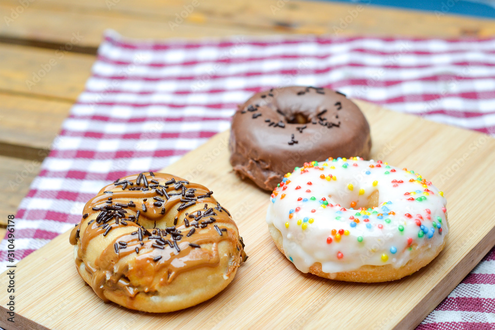 donas de diferentes sabores en tabla de madera Stock Photo | Adobe Stock