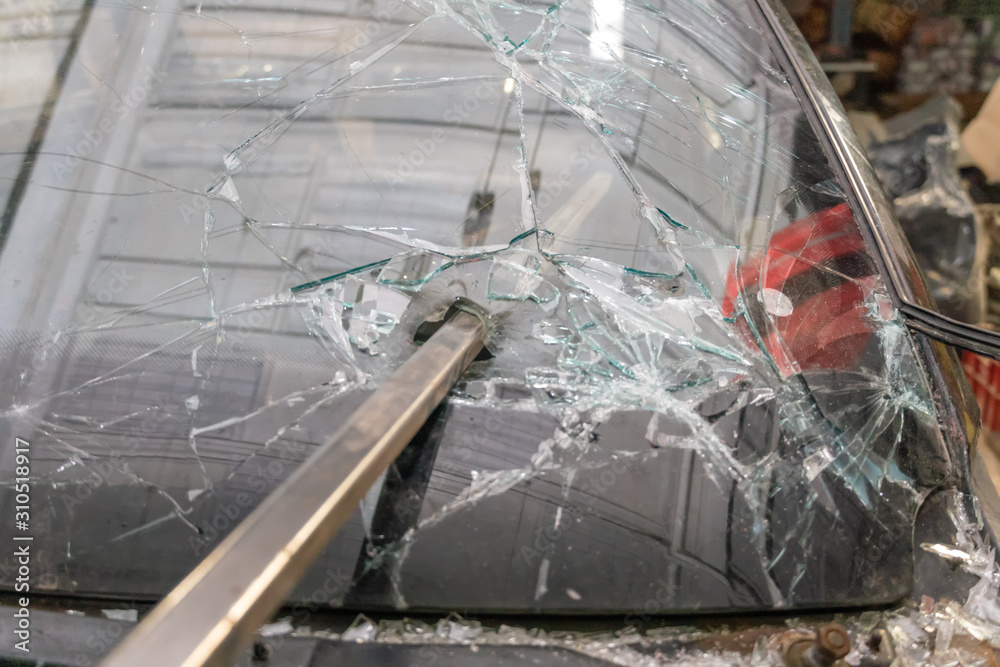 An iron pipe sticks out in the windshield of the car. Damage to the ...
