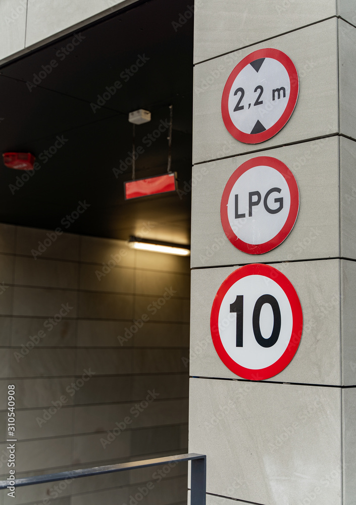 Modern underground parking lot entrance with three prohibition signs ...