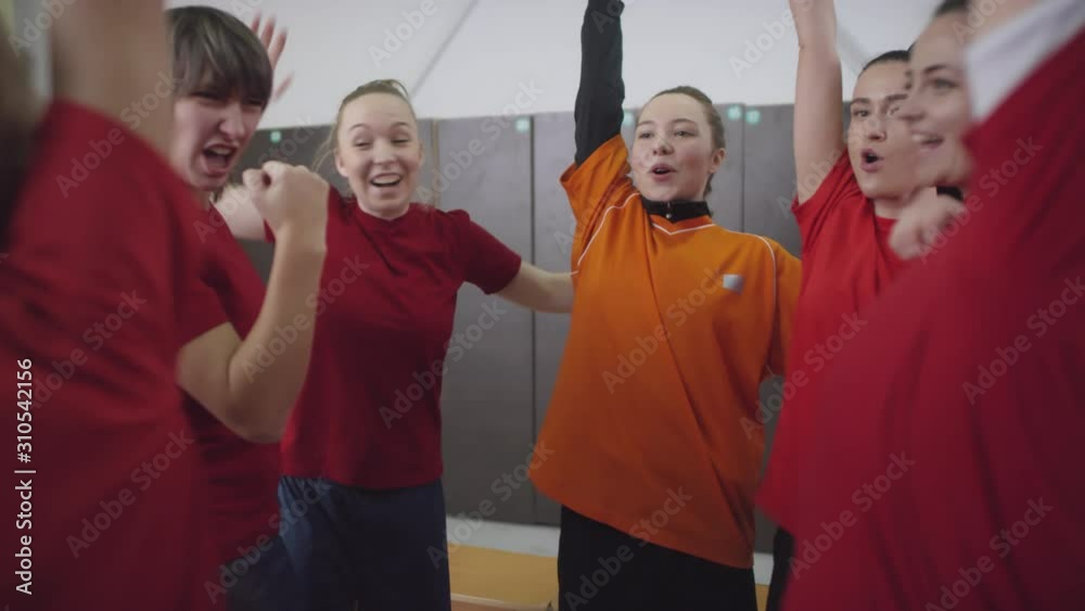 Team of young excited female soccer athletes in sports uniform stacking ...