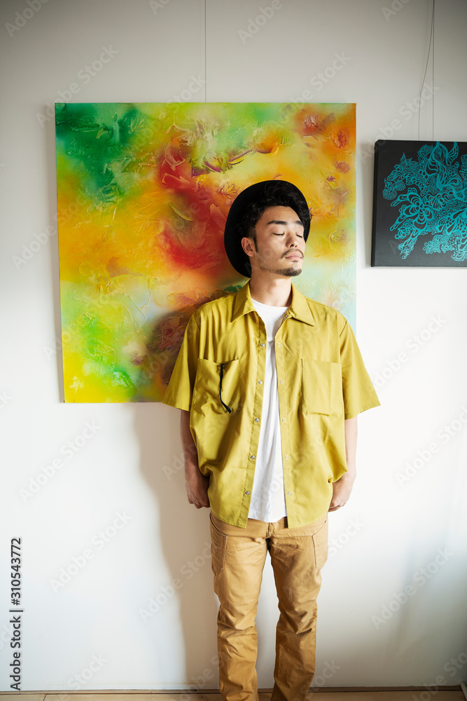 Japanese man standing in front of abstract painting in an art gallery ...