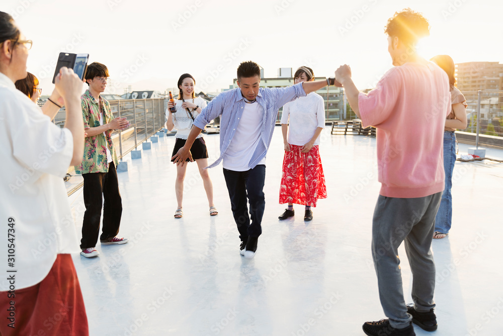 Group of young Japanese men and women dancing on a rooftop in an urban ...