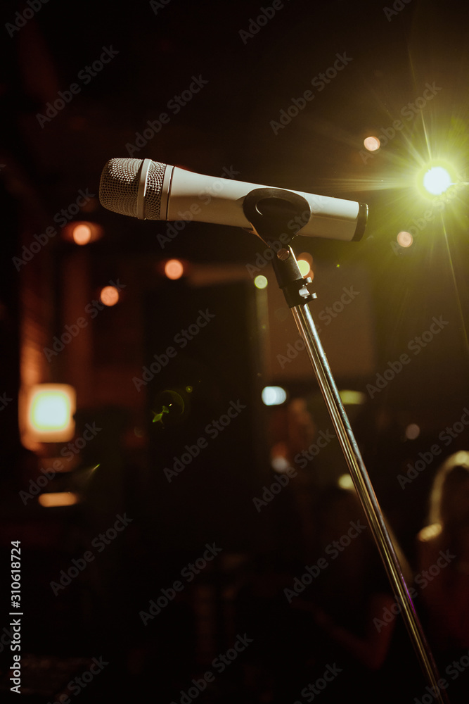 Professional stage microphone in bright spot light beam over dark ...