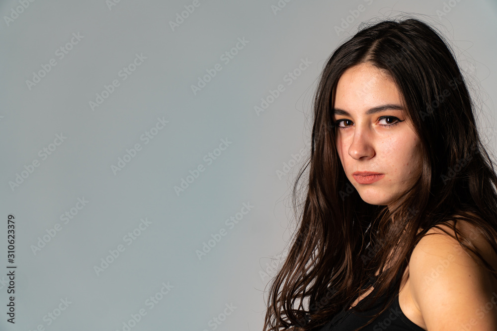 Portrait of disconcerted young woman in light clothes looking aside ...