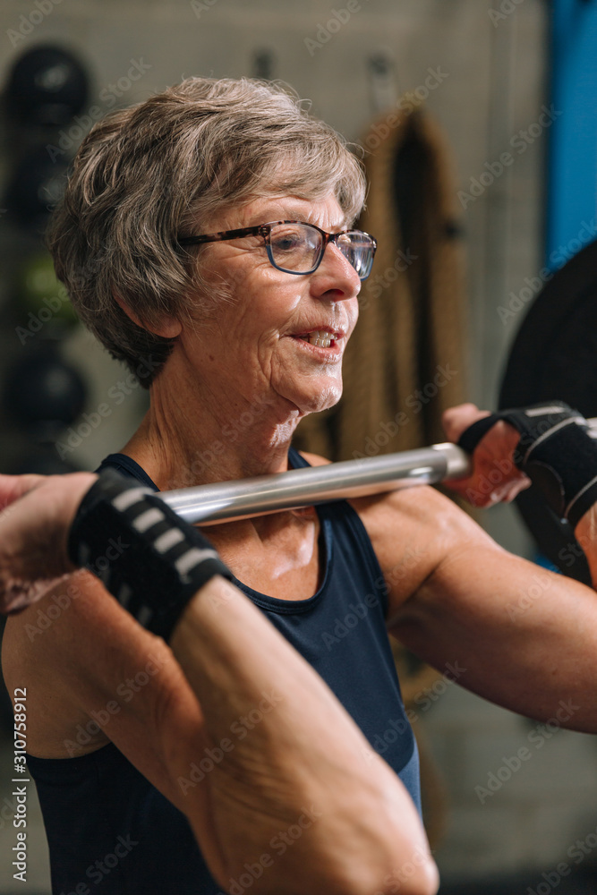 A fit mature woman in her seventies weightlifting in a gym. Stock Photo ...