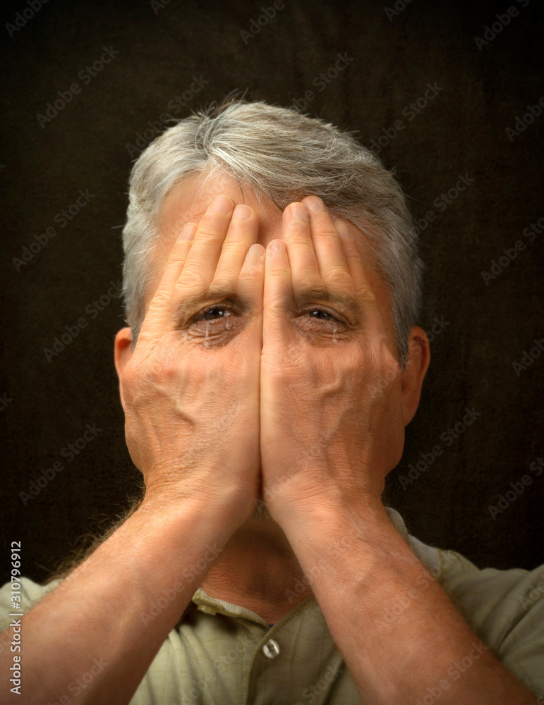 Crying man is trying to hide his face with his hands and not show his ...