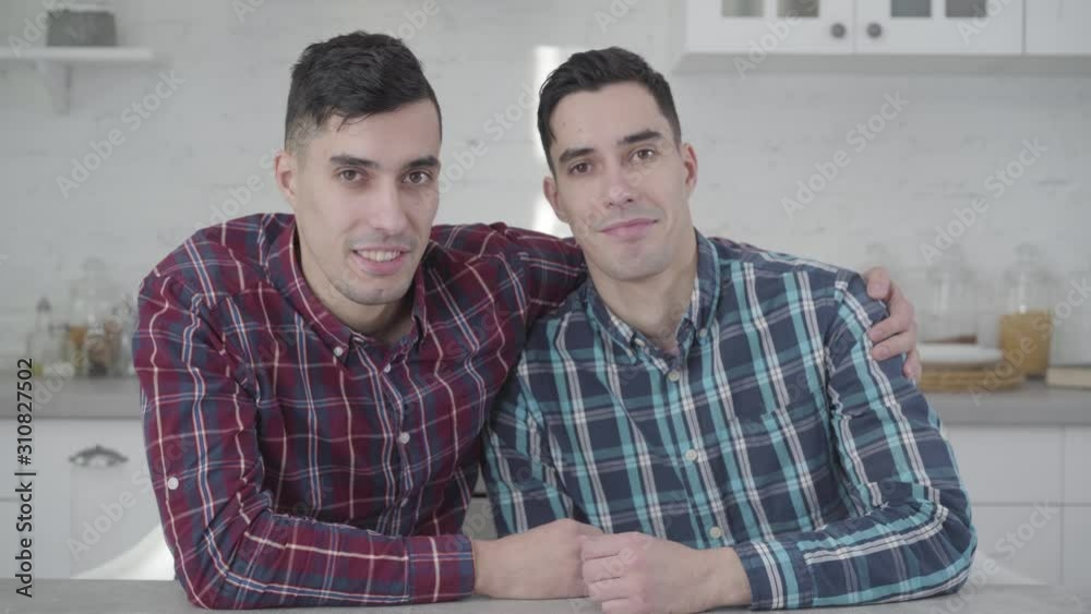 Close-up of two adult Caucasian twin brothers talking to each other ...