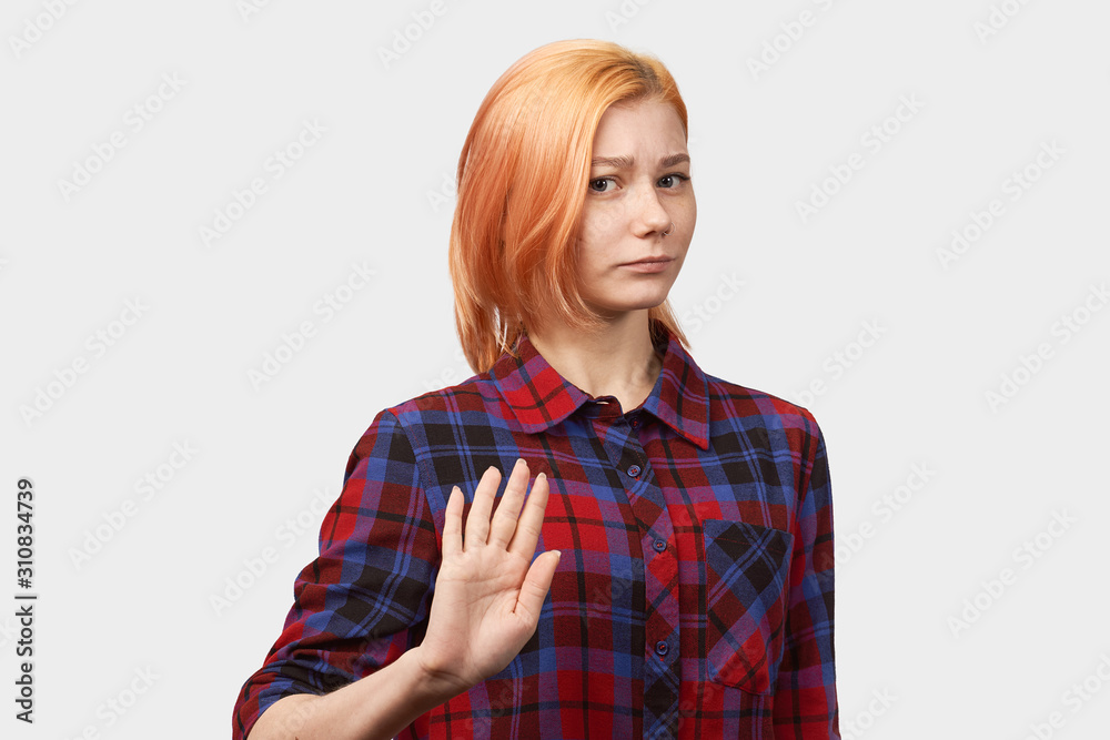 Beautiful young woman feels danger, stretches hand, holds palm in stop ...