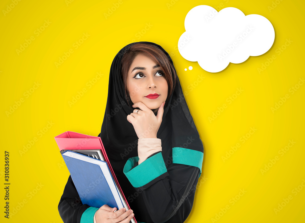 Arabic student wearing hijab holding a book in her hand thinking with ...