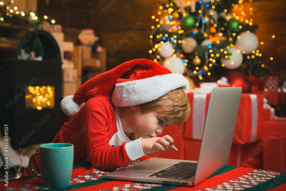Christmas little boy typing letter to Santa Claus on a computer at home ...