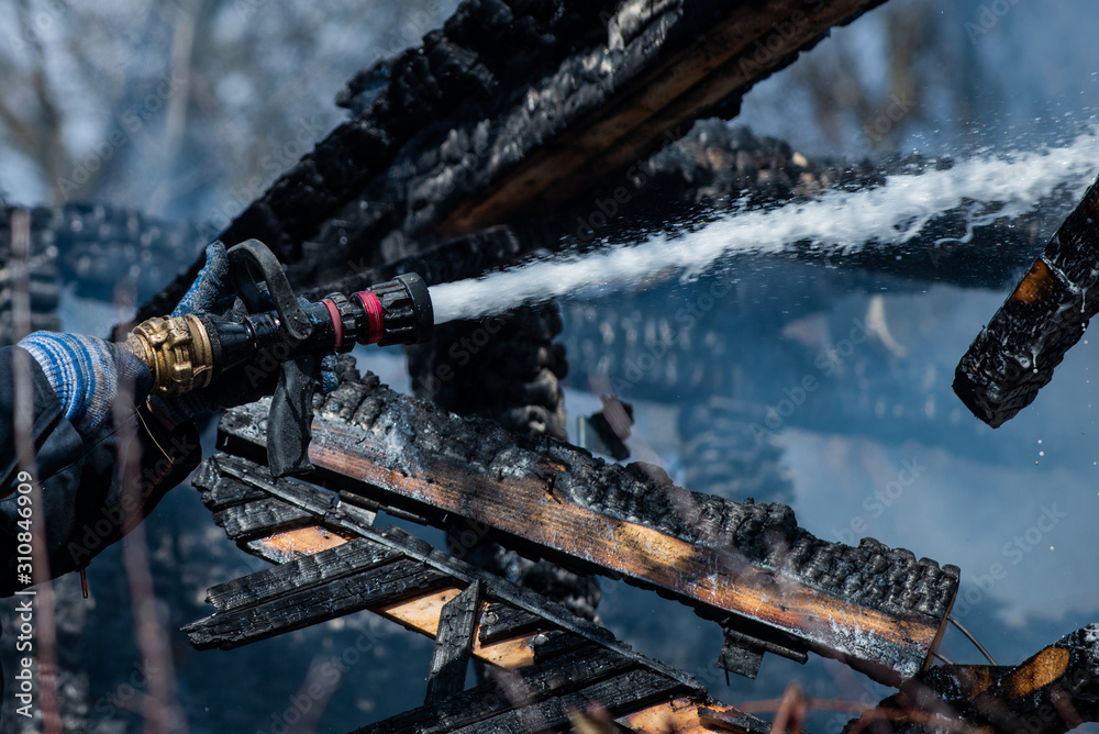 Water jet splashing from a fire fighting firehose nozzle. Firefighter ...