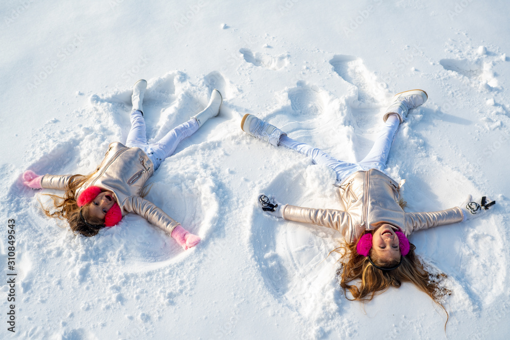 Two Girls on a snow angel shows. Children playing and making a snow ...
