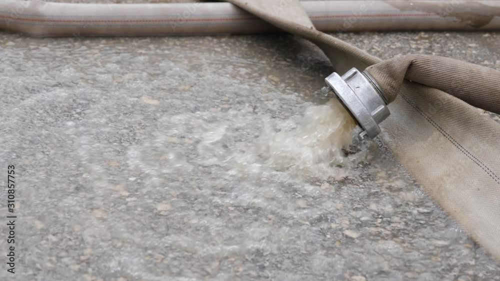 Close up footage of a water hose at a flooded area, people are pumping ...