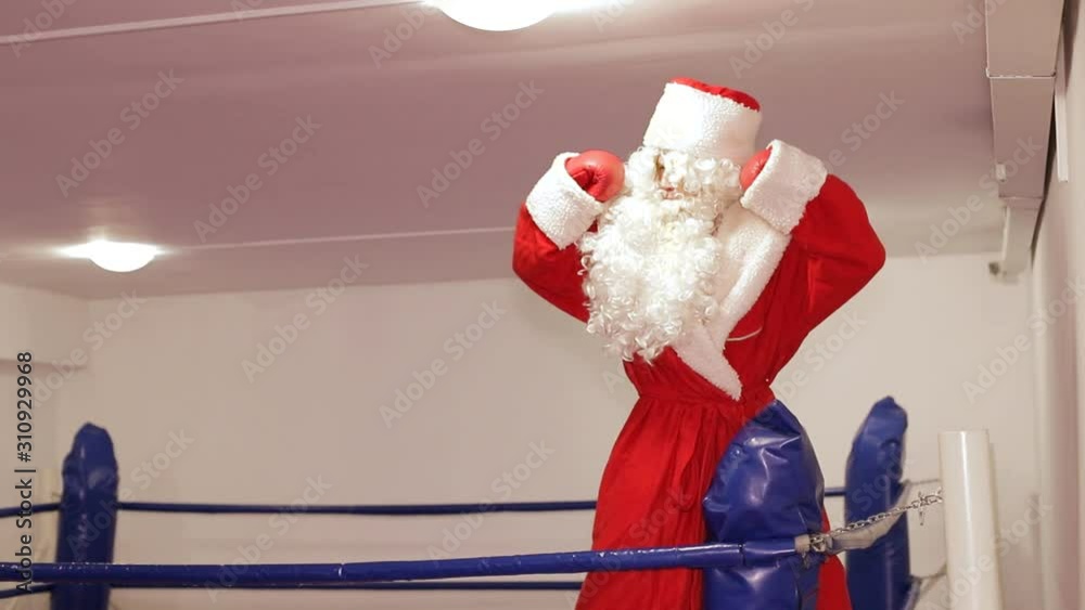 Muscular man in Santa Claus suit with boxing gloves trains in the ring ...