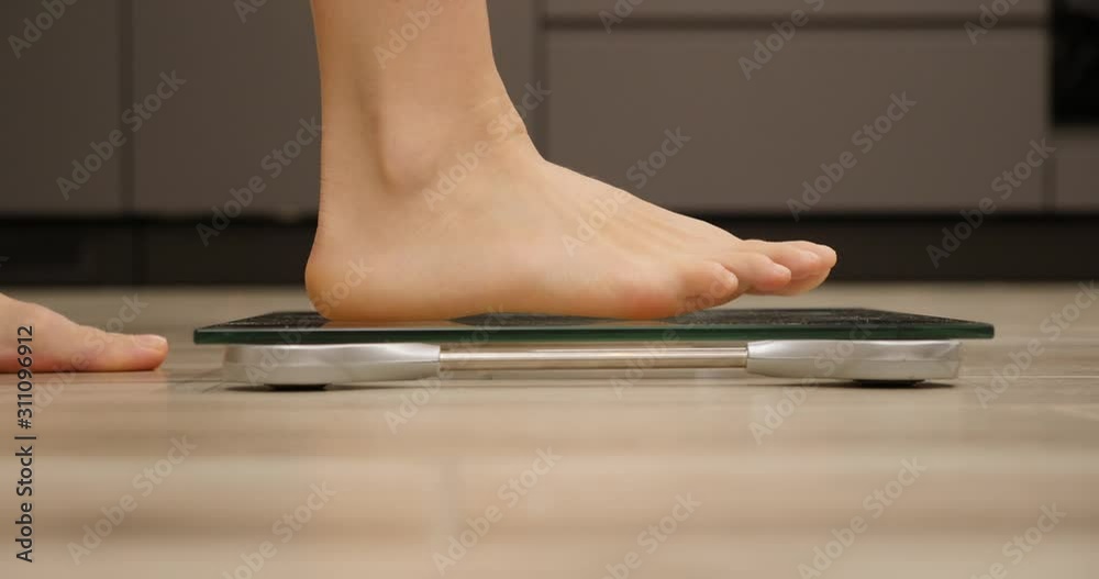 Woman on body scales. Girl barefoot checking weight, close up, side ...
