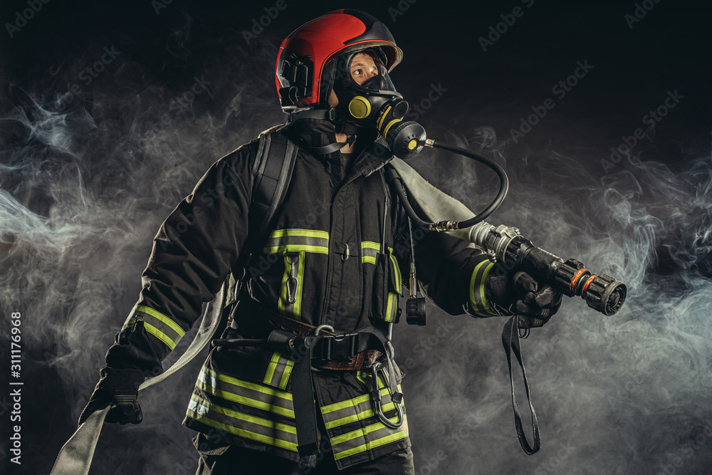 brave firefighter extinguishing fire in smoke, using special equipment ...