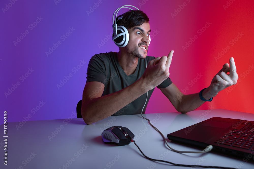 Portrait of an angry gamer playing video games on computer in dark room ...