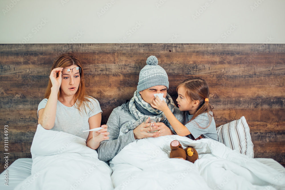 ill caucasian family lying on bed together, suffering from disease ...