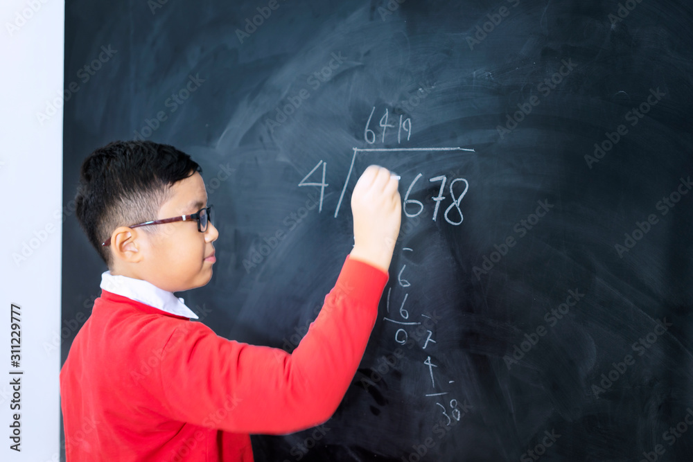 Side view of an adorable boy solving calculations Stock Photo | Adobe Stock
