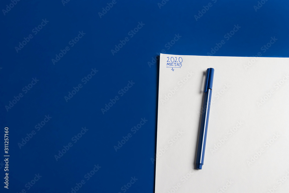 Lapicero negro con azul sobre escritorio azul clásico con hoja de papel ...