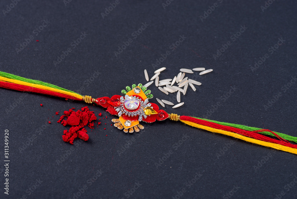 Raksha Bandhan : Rakhi with rice grains and kumkum on black background ...