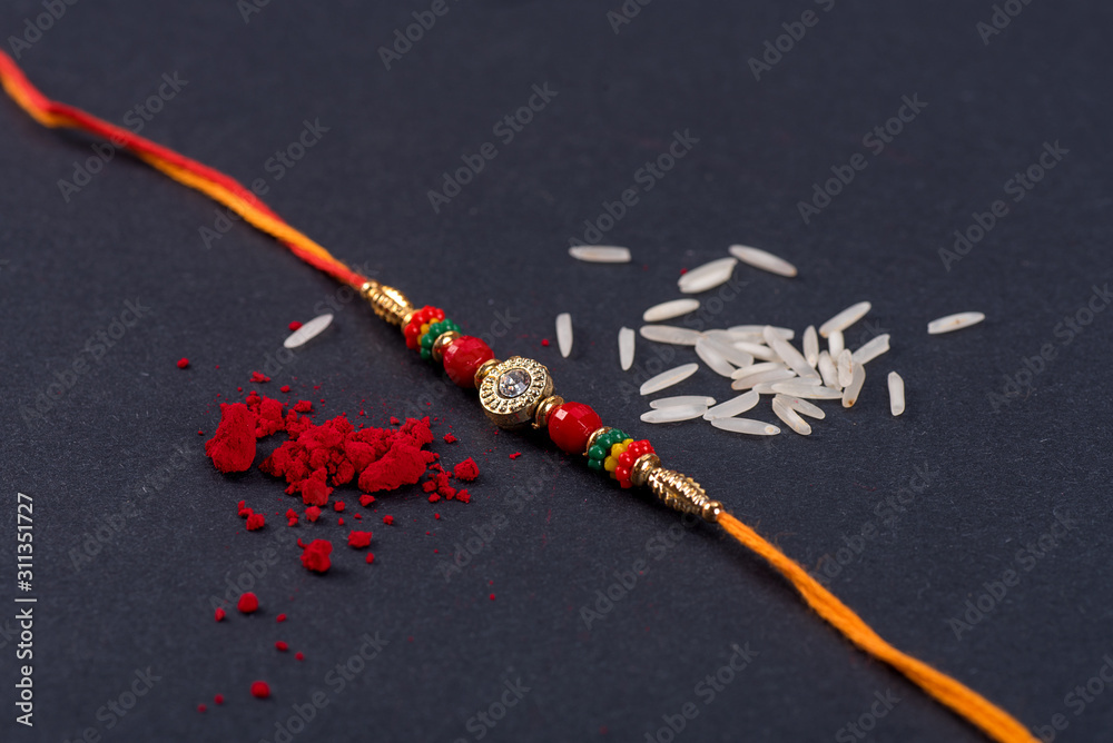 Raksha Bandhan : Rakhi with rice grains and kumkum on black background ...
