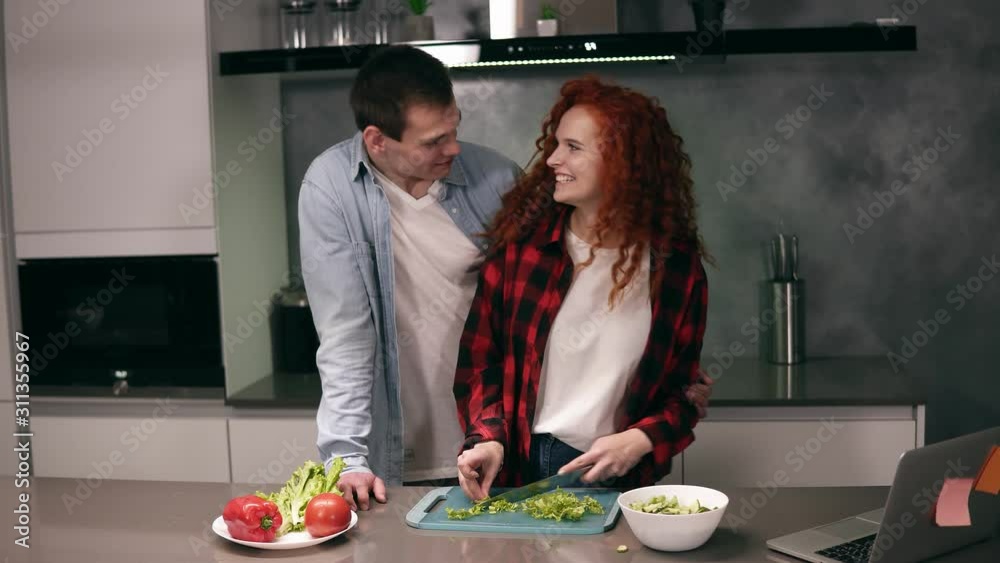 Funny couple while cooking together in grey coloured kitchen, young ...
