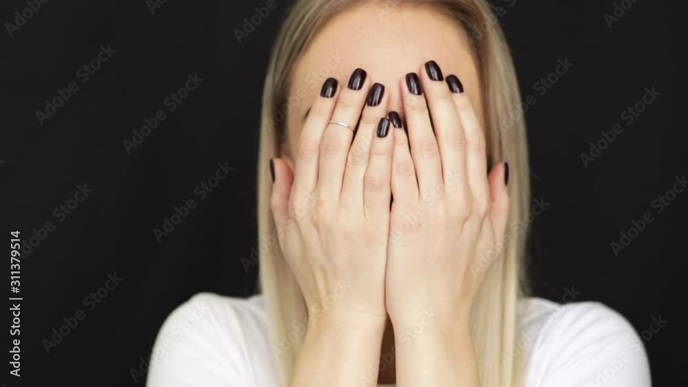 blonde with big red lips and wide smile covers her face with her hands ...