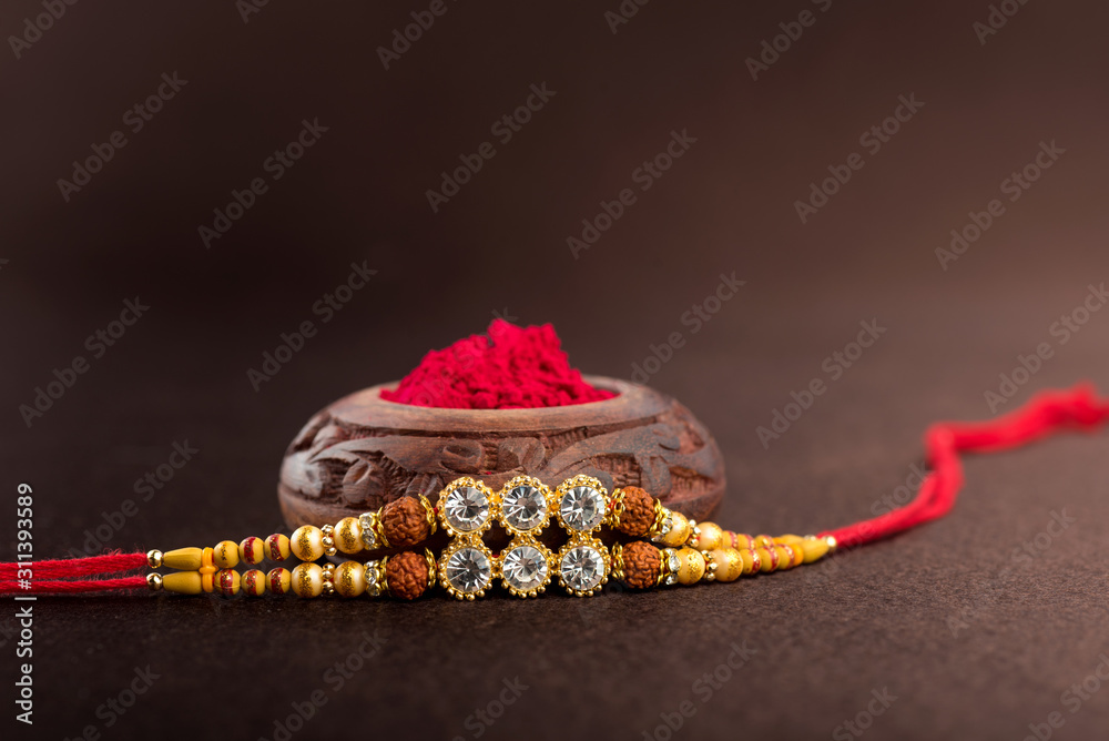 Raksha Bandhan background with an elegant Rakhi, Rice Grains and Kumkum ...