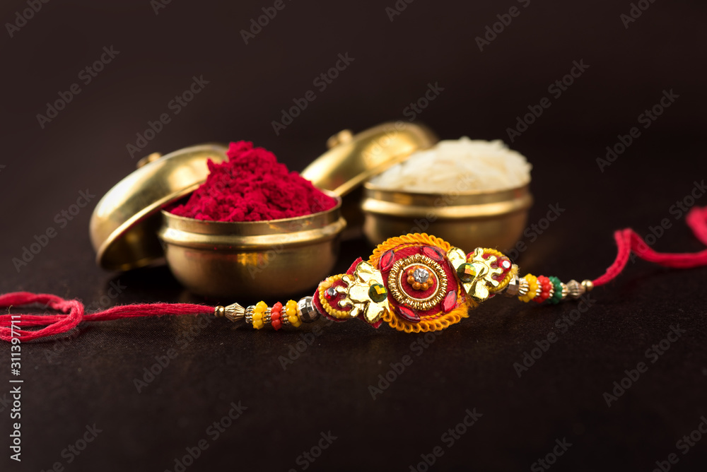 Raksha Bandhan background with an elegant Rakhi, Rice Grains and Kumkum ...