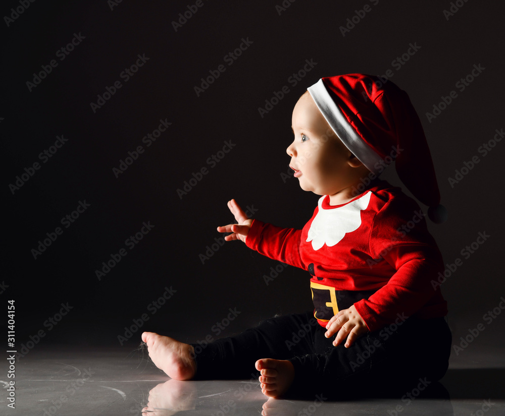 Fascinated baby boy toddler in red santa claus costume is sitting on ...