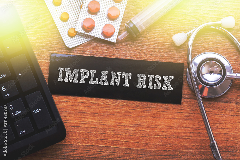 IMPLANT RISK words written on label tag with medicine,syringe,keyboard ...